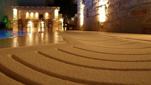 Maquete de um edifício com área de piscina, paredes de pedra e uma pequena estrutura com luzes.