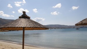 Uma praia com guarda-sóis de palha e espreguiçadeiras.