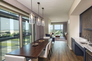 Cozinha moderna com uma ilha grande, área de jantar com mesa comprida e vista para a cidade através de grandes janelas.