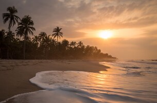 Na praia, areia branca, barracas de praia de cortesia, guarda-sóis 