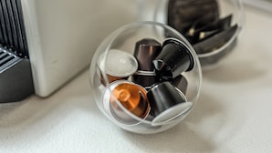 Um recipiente de vidro transparente com vários objetos de metal no interior, sobre uma superfície branca.