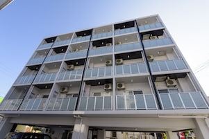 Um edifício com vários andares, varandas, aparelhos de ar condicionado e entrada de garagem.