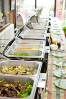 Buffet com diversas estações de comida, incluindo saladas, carnes e bebidas.