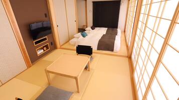 Um quarto tradicional japonês com tatames, uma cama com cabeceira escura, uma televisão e uma pequena mesa de madeira.