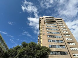 Um edifício de vários andares com céu claro e algumas nuvens.