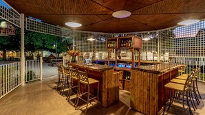 Uma área de bar ao ar livre com móveis e teto de madeira.
