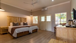 Quarto com cama de casal, cabeceira de madeira, mesas de cabeceira, ventilador de teto e escrivaninha de madeira com cadeira.