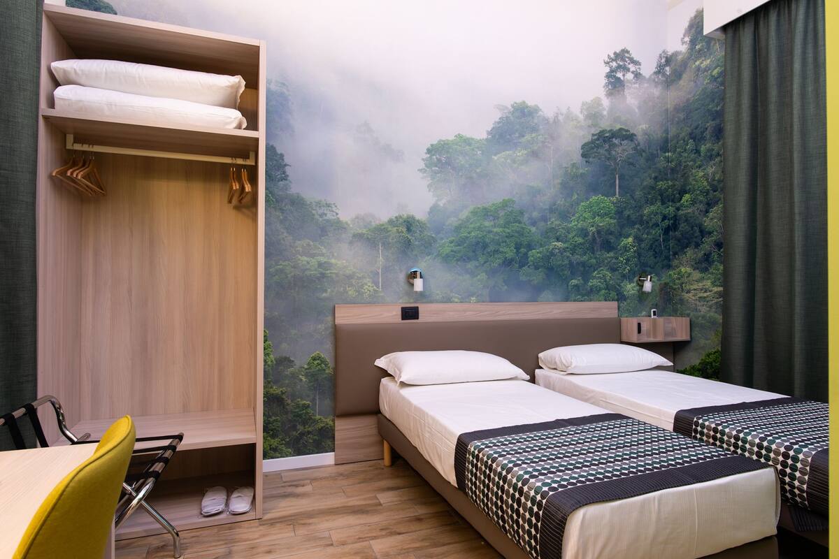 Quarto de hotel com cama, escrivaninha e guarda-roupa.