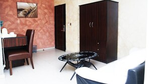 Um quarto com uma mesa de jantar, uma cadeira, uma mesa de centro redonda e um guarda-roupa.