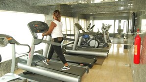Uma academia com esteiras, equipamentos de exercícios e um extintor de incêndio.