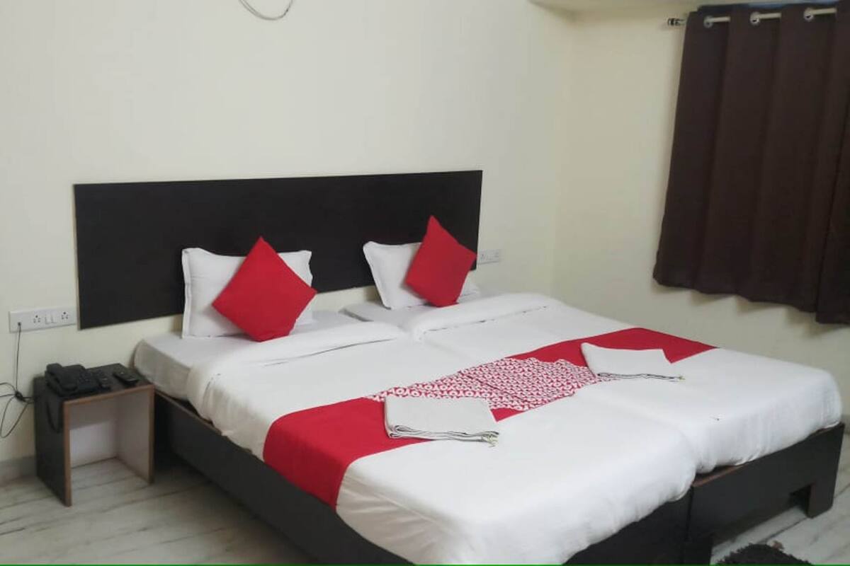 Quarto de hotel com cama, mesa de cabeceira e telefone fixado na parede.