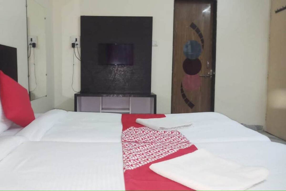Quarto de hotel com uma cama, uma TV fixada na parede e uma porta com design circular.
