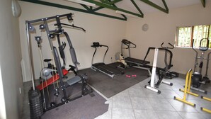 Uma academia com diversos equipamentos de exercício, incluindo esteira, aparelhos de musculação e halteres.