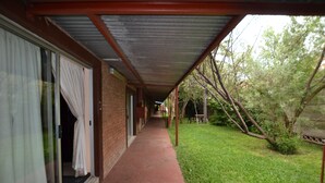 Uma galeria coberta com um caminho de tijolos que leva a um edifício com grandes portas de vidro e uma cortina branca.