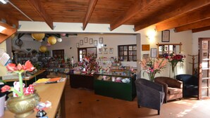 Um interior aconchegante com vigas de madeira, um balcão com diversos itens e uma área de estar com cadeiras.