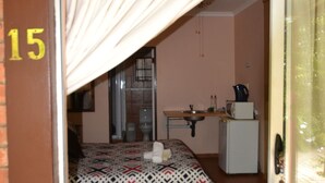 Um quarto com uma cama, uma pequena cozinha e uma porta com o número 15.