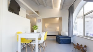 Um espaço compacto com área de refeições, cama e janela.