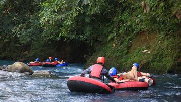 Pessoas praticando rafting em um rio, cercadas por vegetação.