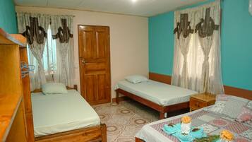 Quarto com duas camas de madeira, um guarda-roupa de madeira, uma mesa de cabeceira de madeira e piso estampado.