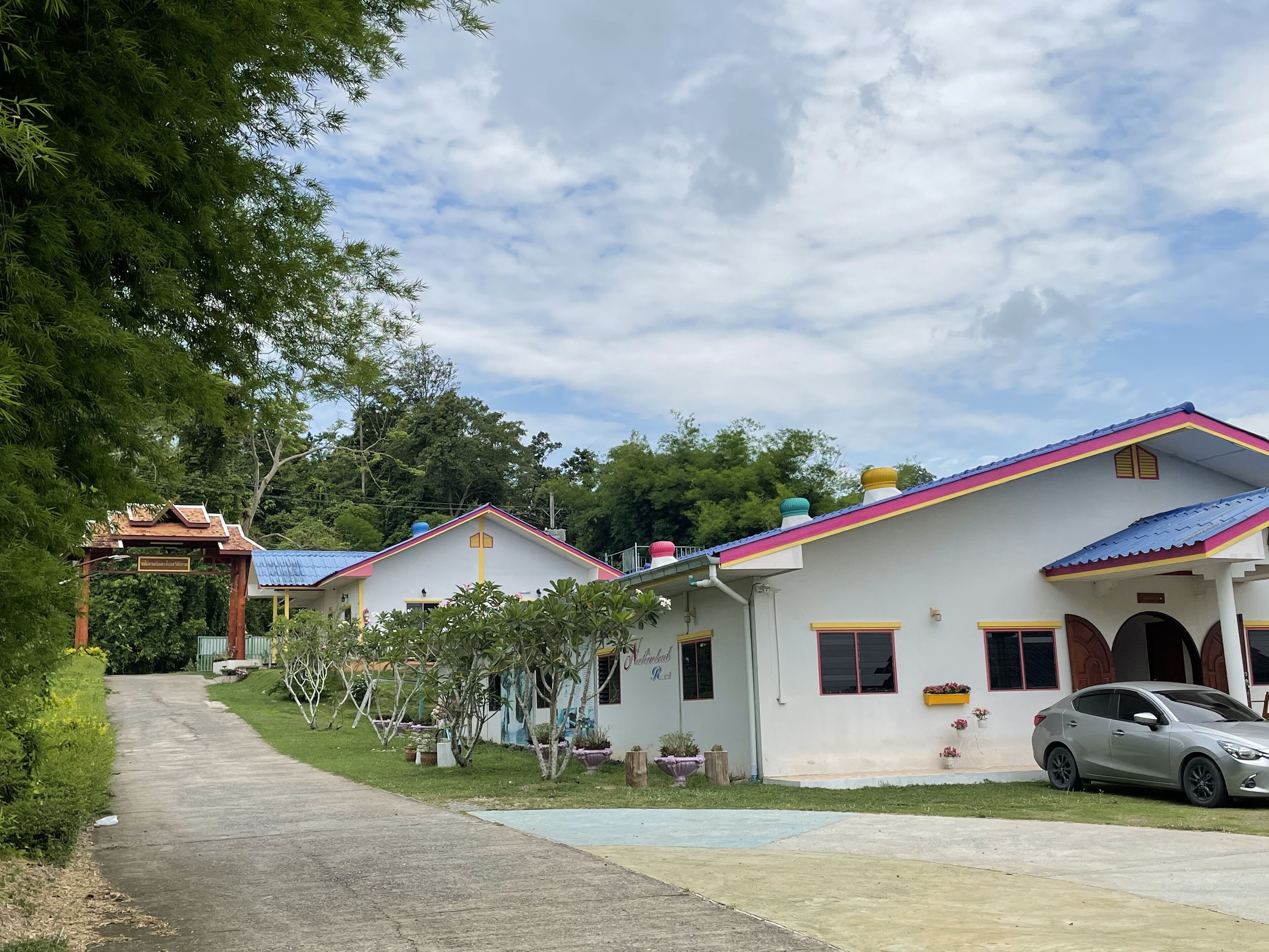 Uma fileira de casas brancas com telhados coloridos, um caminho de entrada pavimentado e um carro estacionado.