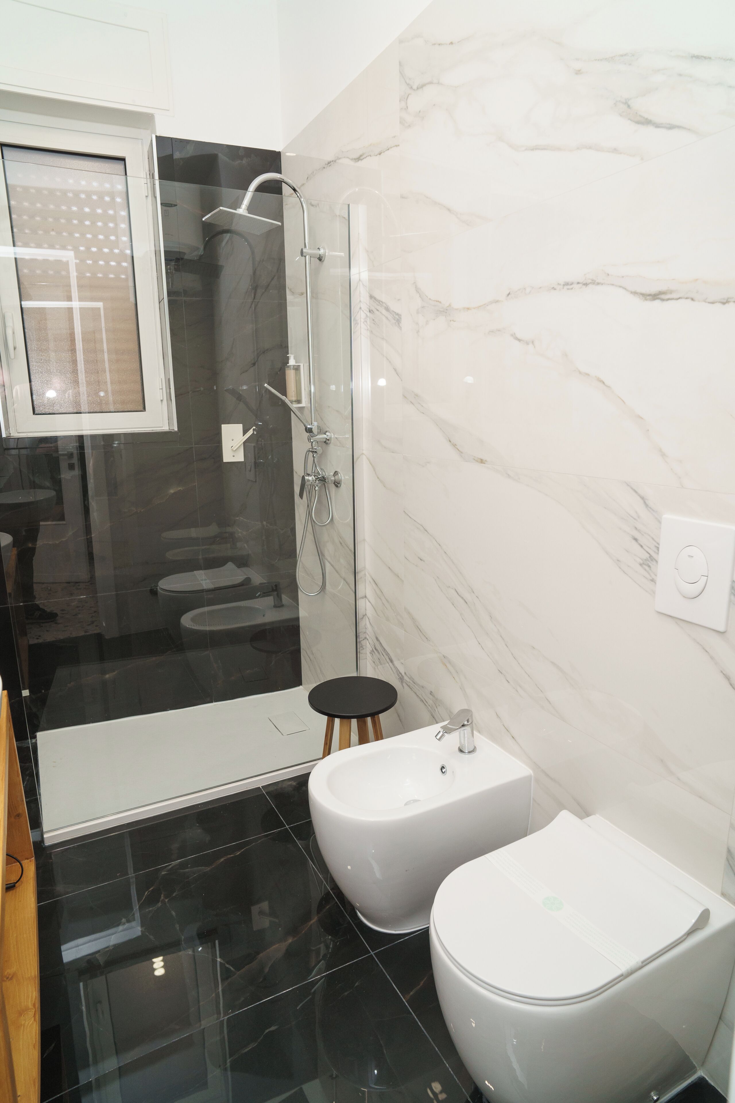 Uma casa de banho moderna com chuveiro em cabine de vidro, sanita e bidé.