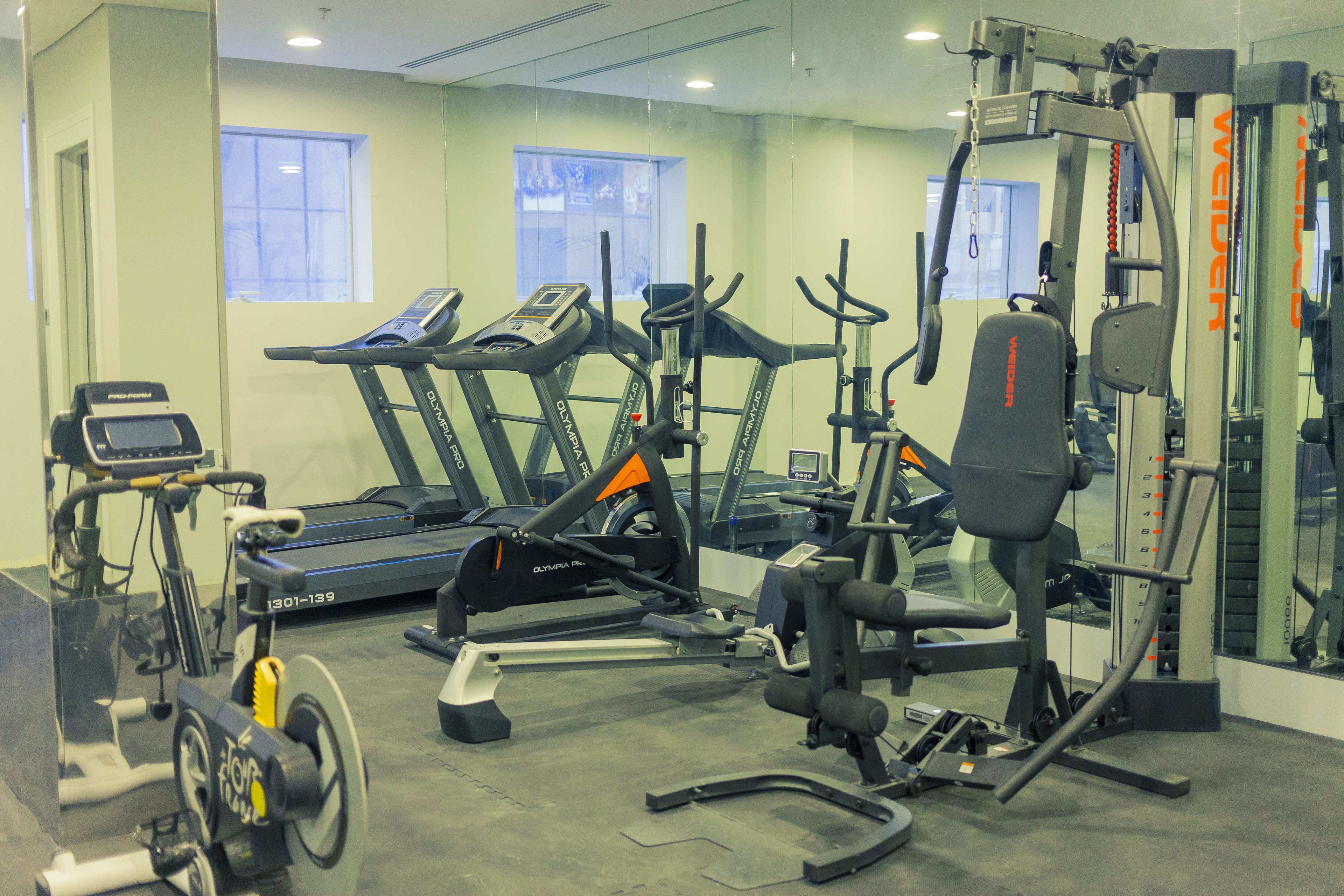 Uma academia com esteiras, aparelhos de musculação e bicicleta ergométrica.