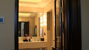 Casa de banho de hotel com um espelho grande, uma pia e um porta-toalhas.