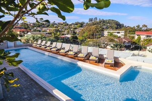 Piscina com espreguiçadeiras e vista para uma área residencial.