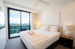 Quarto de hotel moderno com uma cama grande, vista para a cidade e um ventilador de teto.