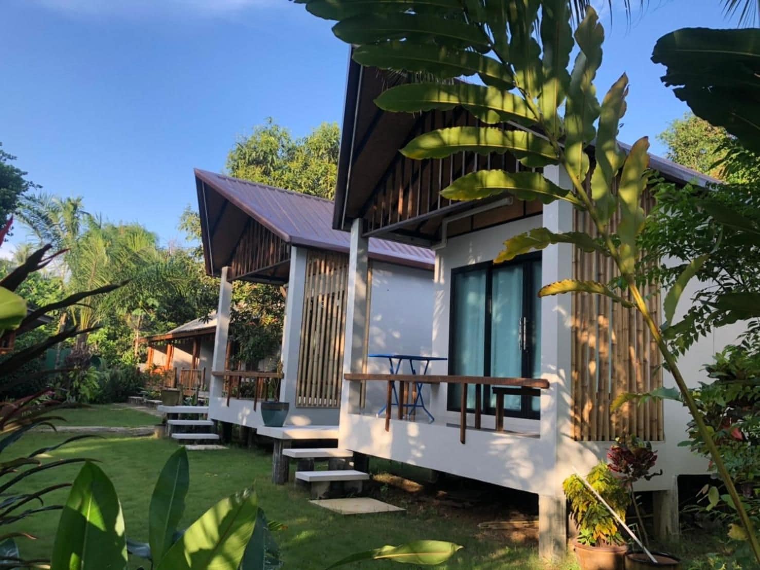Uma casa moderna com varanda coberta, um pequeno jardim e vista para o verde ao redor.