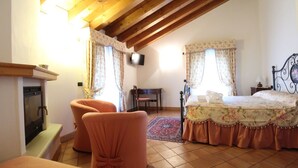 Quarto com cama, televisão, lareira e janela com cortinas.