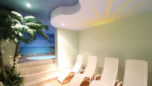 Quarto com vista para a praia, cadeiras reclináveis e uma palmeira.