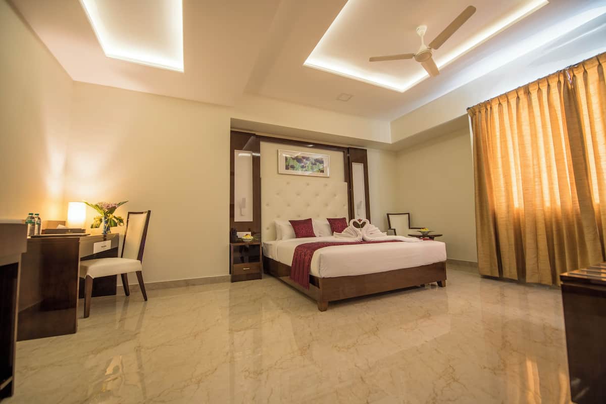 Quarto de hotel com cama, escrivaninha, cadeira e ventoinha no teto.