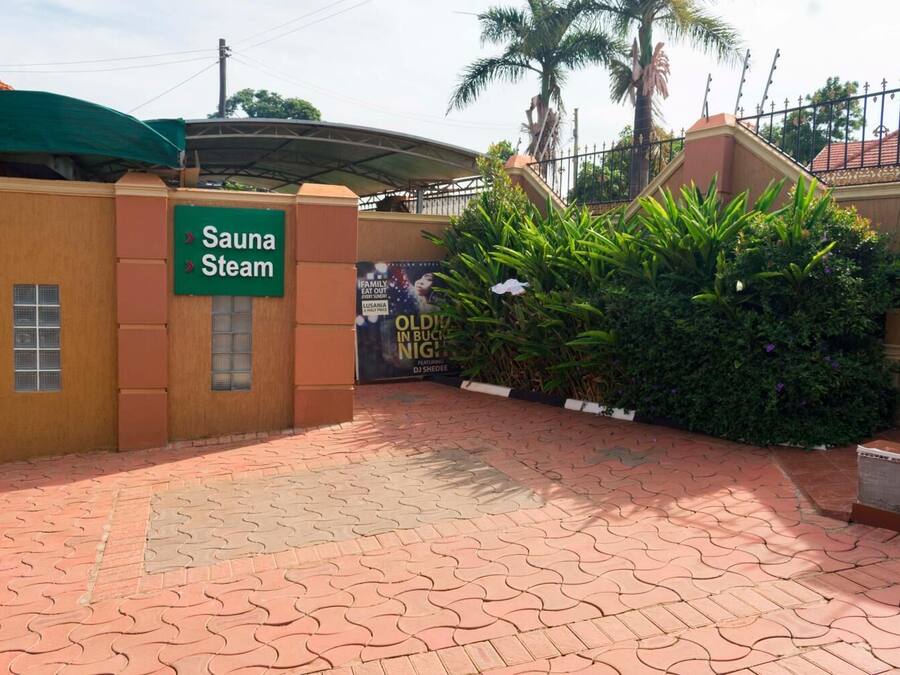Entrada de um spa com uma placa indicando 'Sauna Steam', calçada e um cartaz publicando um evento musical.