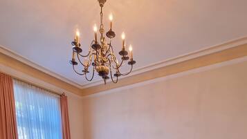 Quarto de hotel com uma cama grande, duas poltronas, um candelabro e vista para o exterior.