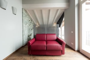 Um sofá vermelho num quarto moderno com uma parede ripada e teto de madeira.