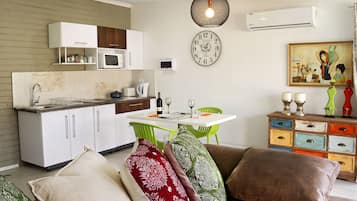 Uma cozinha moderna com armários brancos, micro-ondas e uma área de refeições com uma cadeira verde e uma mesa branca.