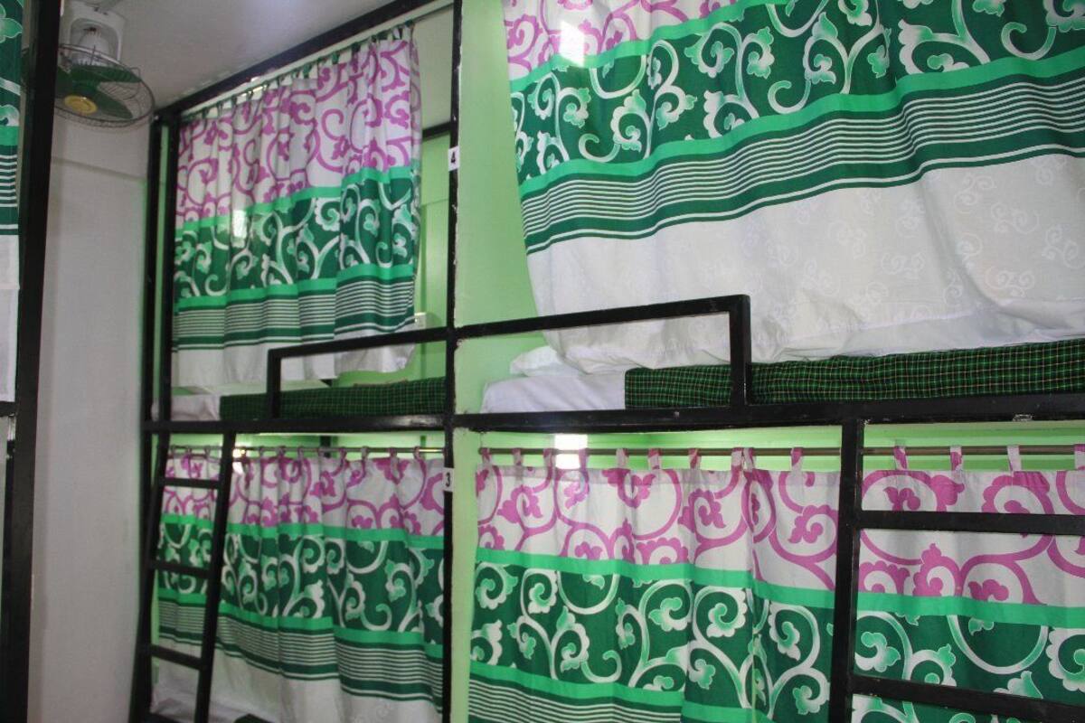 Quarto com beliches e cortinas estampadas.
