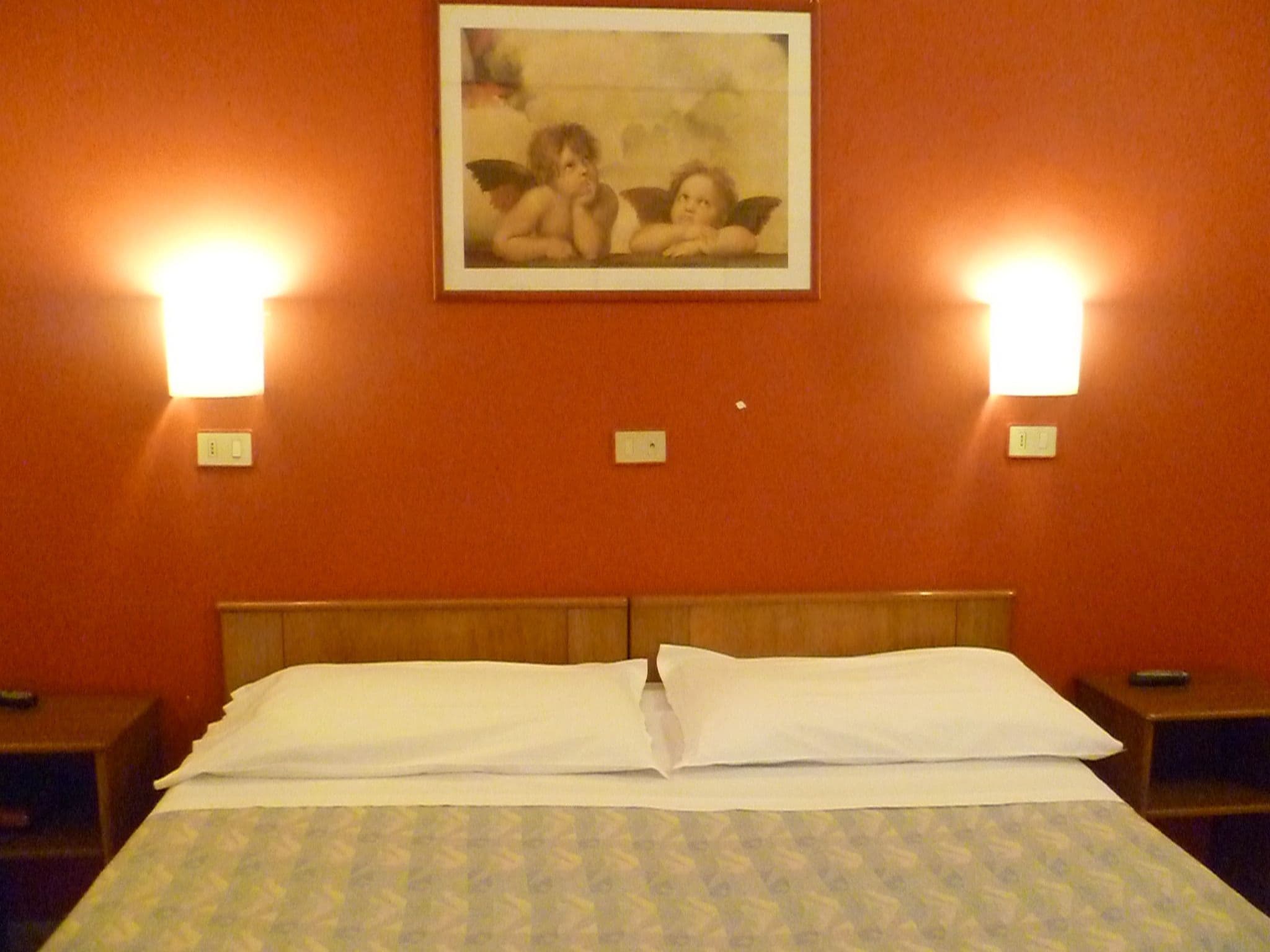 Quarto de hotel com uma cama, duas mesas de cabeceira e um quadro na parede.
