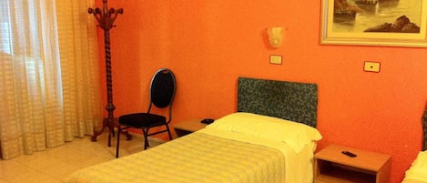 Um quarto com cama, cadeira, mesa de cabeceira e um quadro na parede.