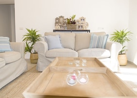 Sala de estar com dois sofás, uma mesa de centro e objetos decorativos em um aparador.