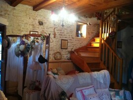 Quarto rústico com escada de madeira, cama com roupa de cama estampada e luminária na parede.