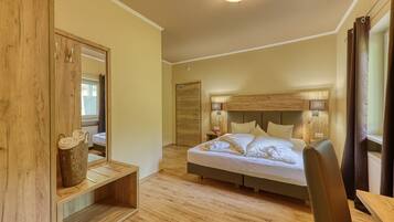 Quarto com guarda-roupa de madeira, cama com roupa de cama branca, mesa de cabeceira e cabeceira com luzes fixadas na parede.