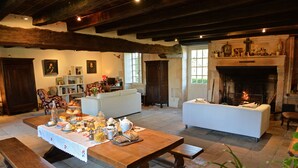 Um quarto acolhedor com uma mesa de madeira posta para o café da manhã, uma lareira e um sofá branco.