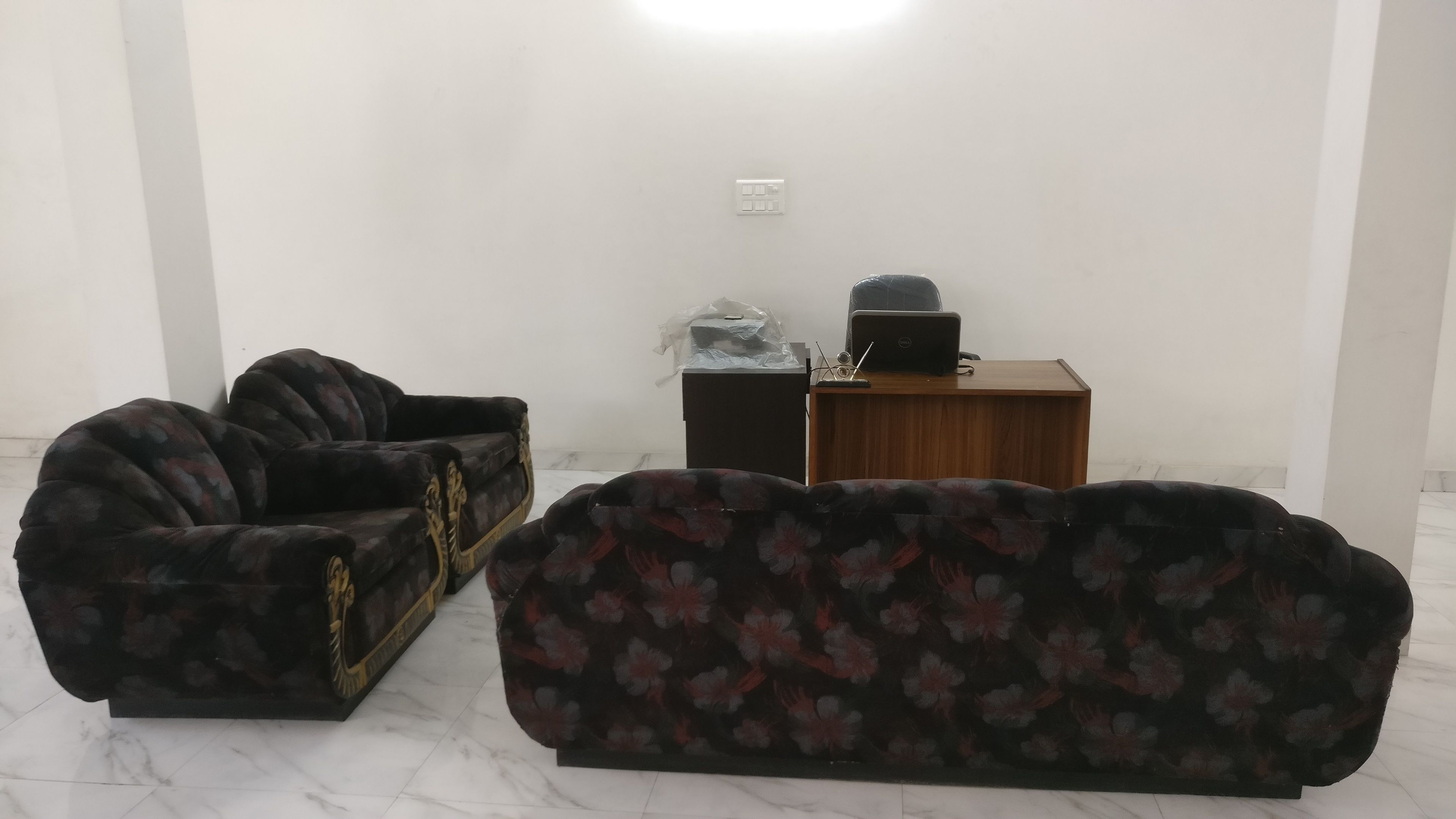 Um quarto com dois sofás, uma escrivaninha de madeira e um laptop.