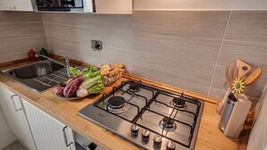 Uma cozinha moderna com fogão de aço inoxidável, pia e bancadas de madeira.