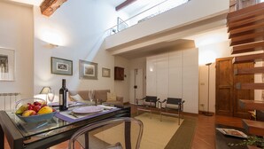 Uma sala ampla com uma mesa de vidro, cadeiras, sofá e escada.
