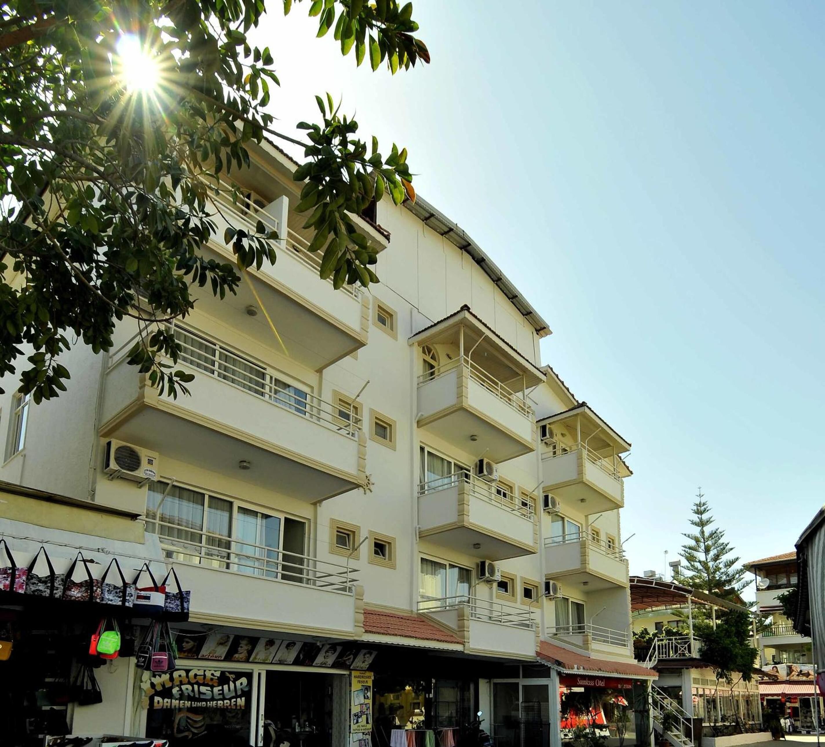 Edifício de vários andares com sacadas, aparelhos de ar condicionado e fachada comercial no térreo.