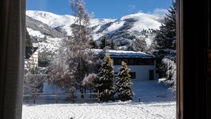 Paisagem nevada com uma casa e montanhas ao fundo.