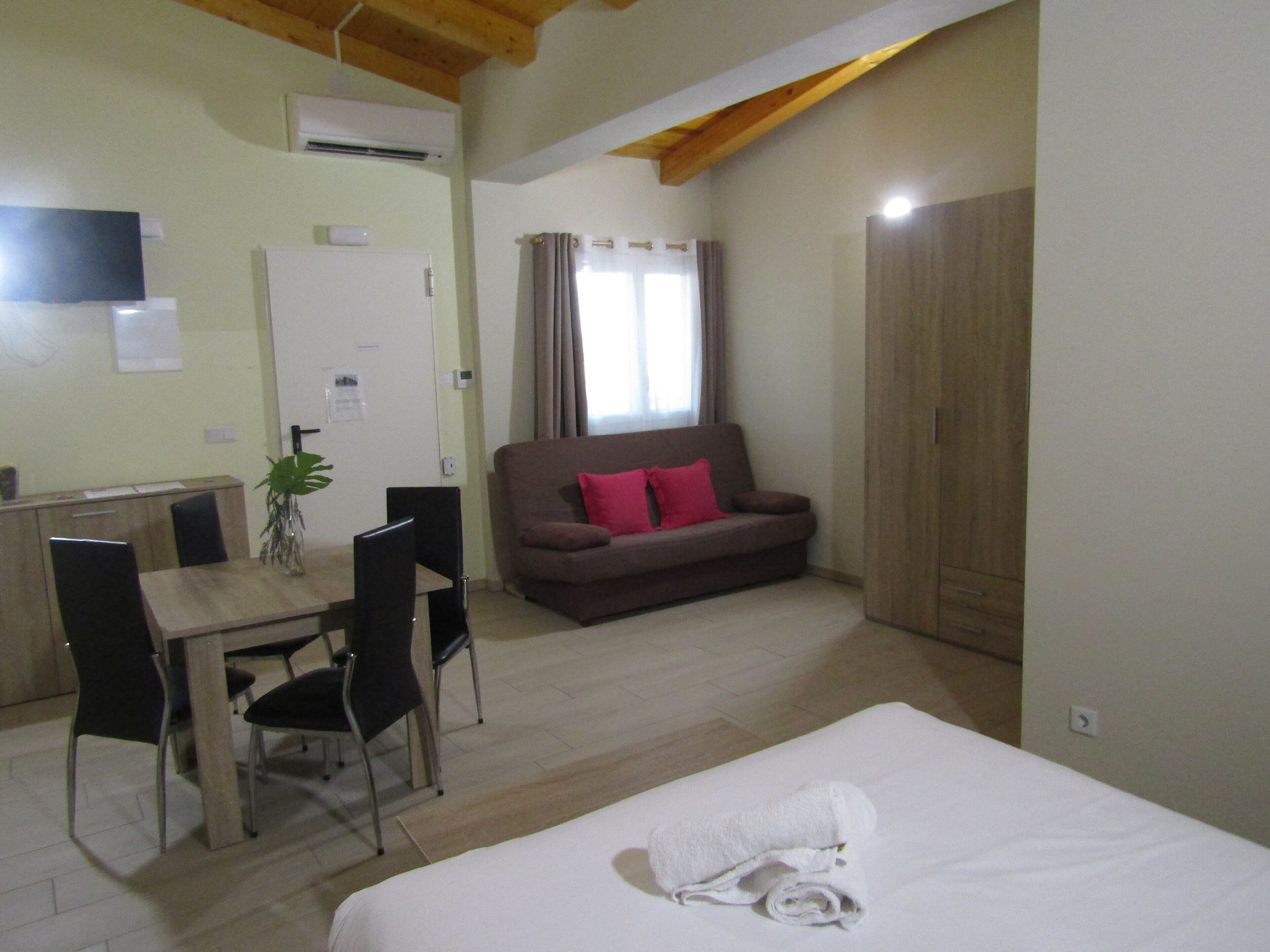 Um quarto com uma cama, uma mesa de jantar com cadeiras, um sofá e um guarda-roupa.